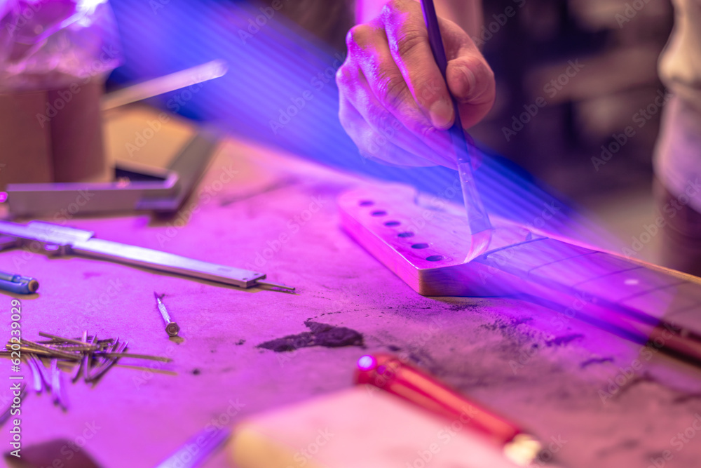 Dusting off an Unstrung Guitar Fretboard and Tools on Table with Blue ...