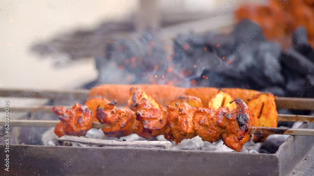 chicken mutton tikka kebab cooking on coal fire with sparks flying and ...
