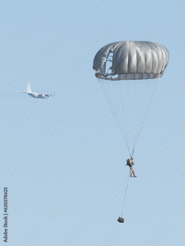 soldier falling with his parachute deployed as he passes behind the ...