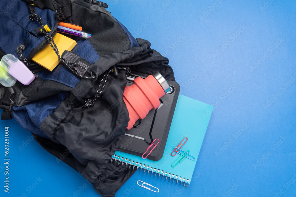 Back to school concept with blue and black book bag backpack, contents ...
