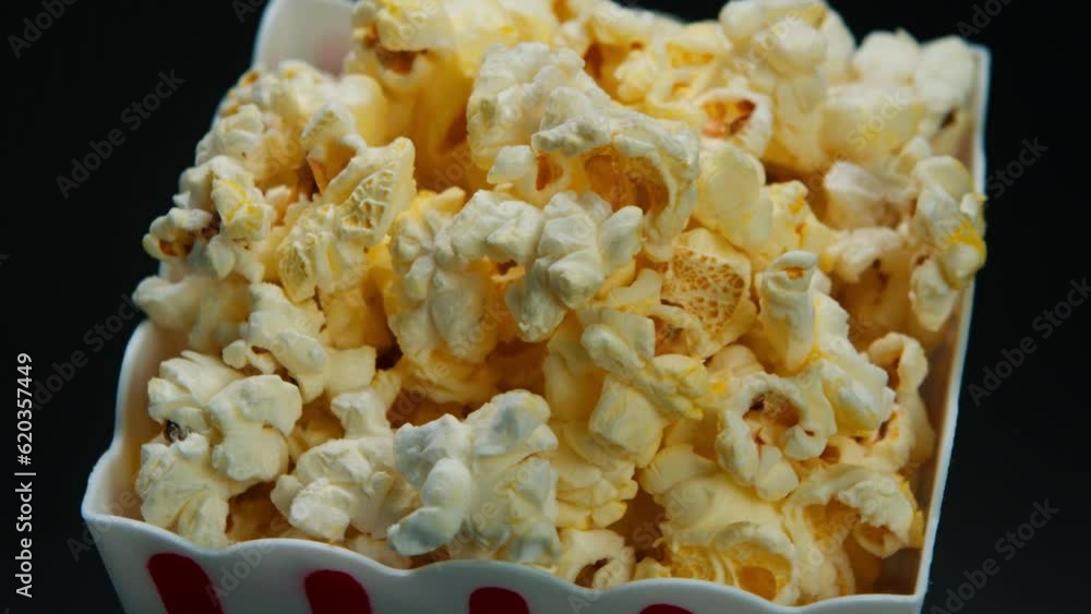 Rotation of air popcorn in a classic box on a black background close-up ...