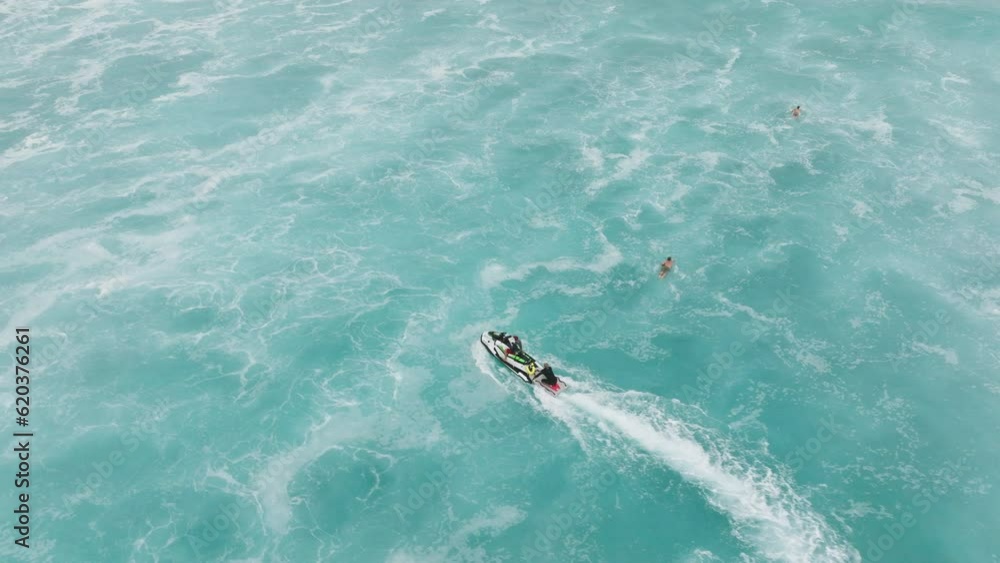 Top down view of Lifeguards riding jet ski to pick up surfers in stormy ...