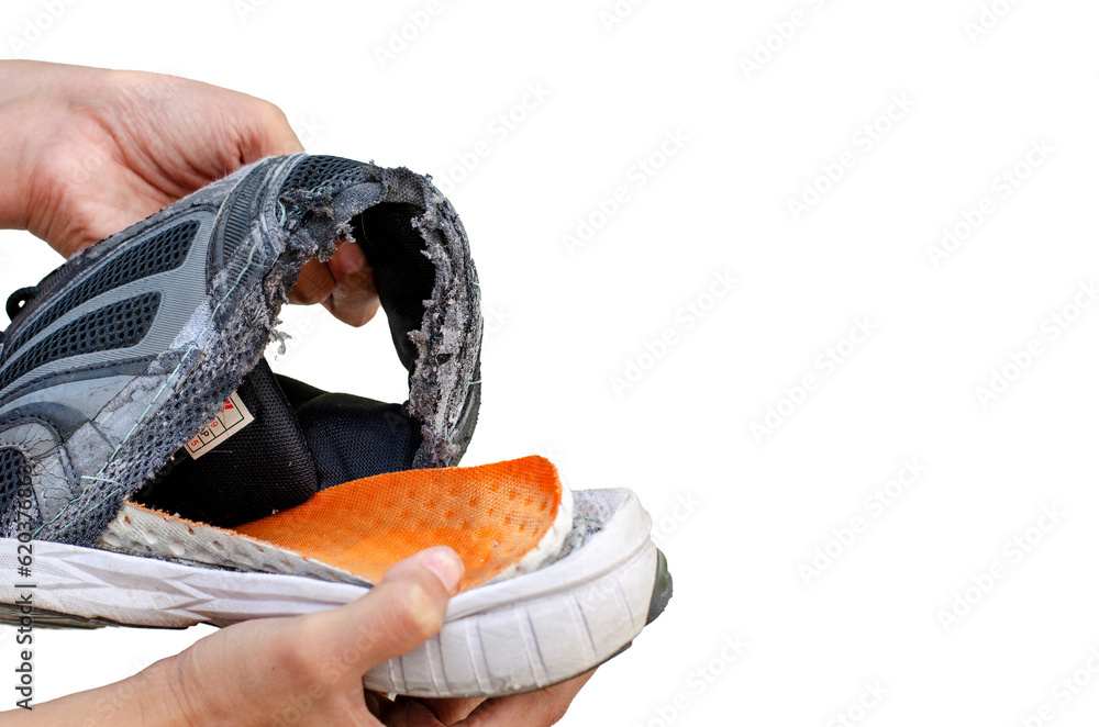 Hand holding an old, broken black shoe behind the heel of the shoe on ...