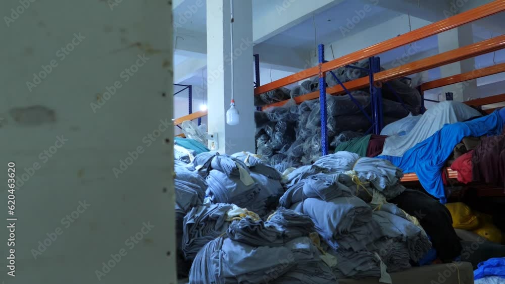 Dolly Reveal Of Storage room with rows of shelf racks full of fabric ...