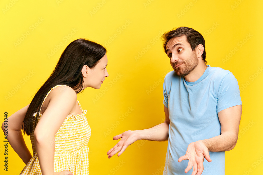 Young woman emotionally talkin to man, asking questions against yellow ...