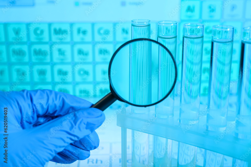 Foto de Scientist with magnifying glass examining test tubes against ...
