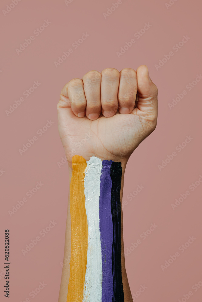 clenched fist and non-binary flag in their arm Stock Photo | Adobe Stock