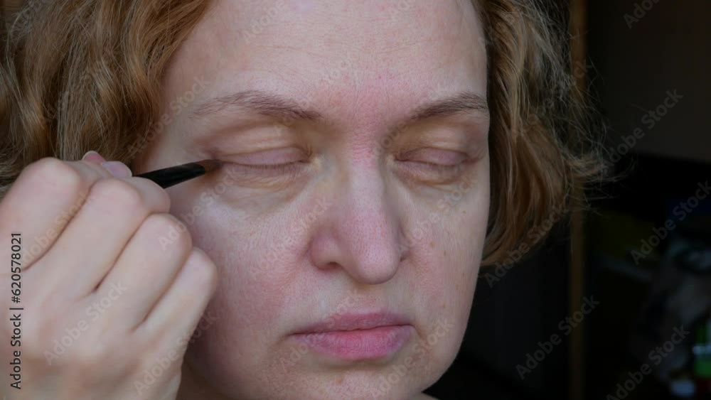 middle aged female's eye with drooping eyelid doing makeup. Ptosis is a ...