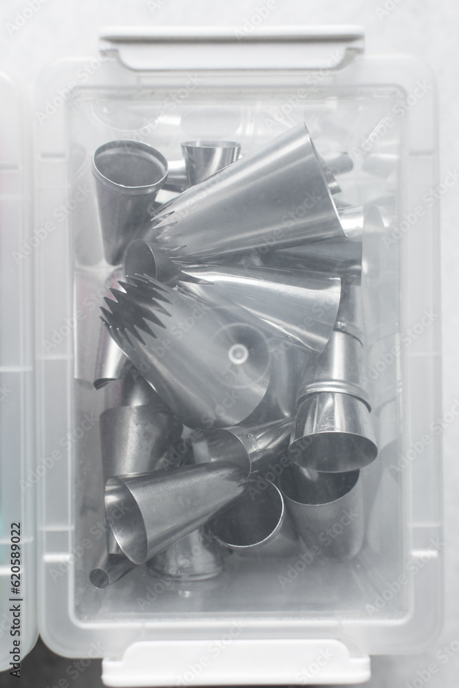 Metal piping tips in a plastic storage container, top view of piping ...