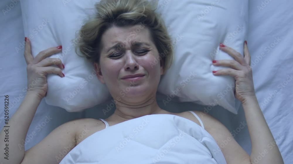 Scared and irritated of noise of rain and thunder woman covering ears ...