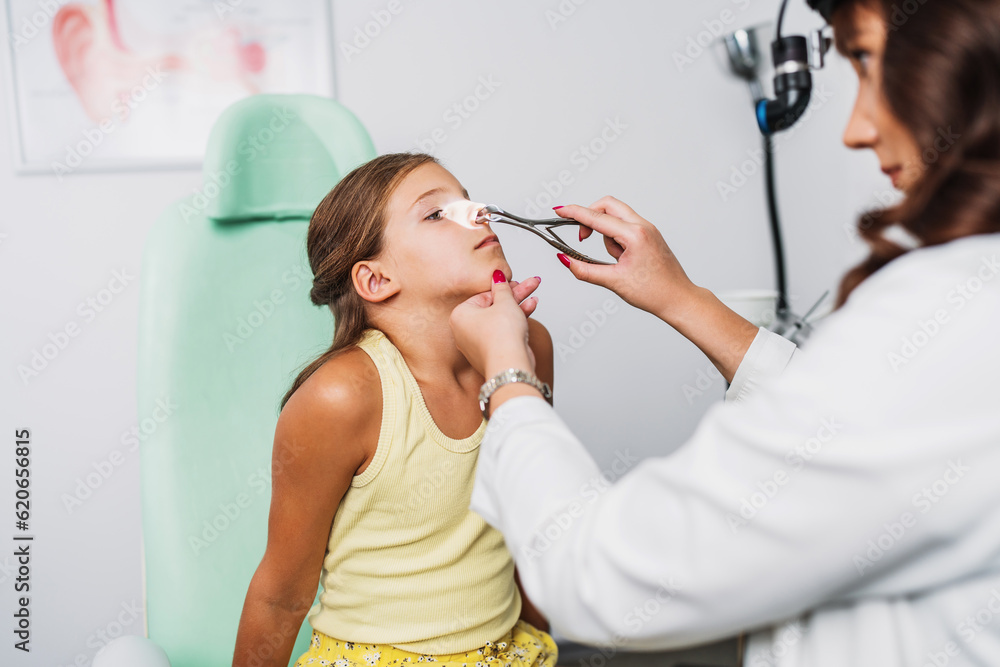 Female audiologist examining girl ear using otoscope in doctors office ...