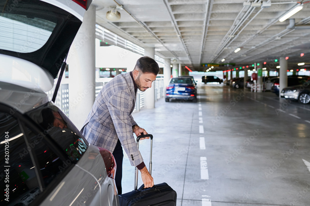 Man taking luggage from a car in an airport parking lot Stock Photo ...
