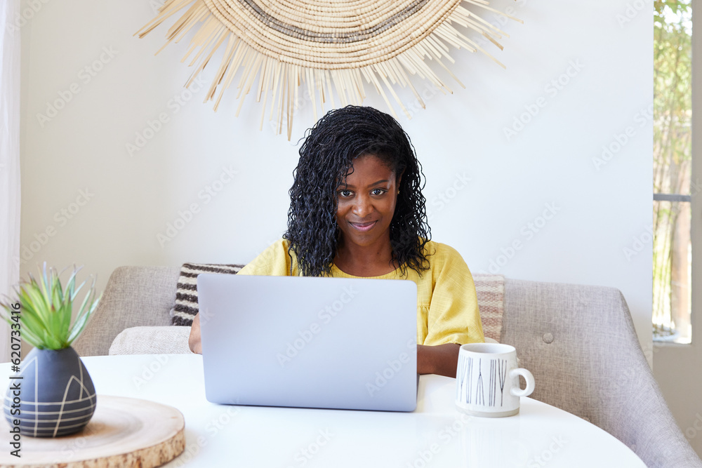 Black woman WFH working from home on computer at dining room table ...