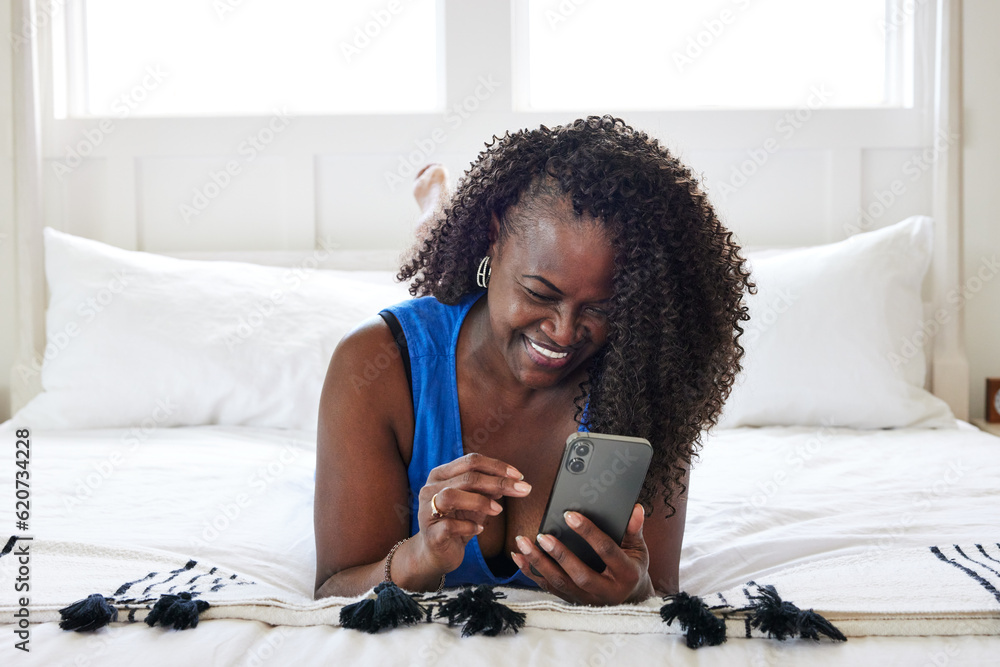 Mature Black woman texting on phone at home in bed smiling Stock Photo | Adobe Stock
