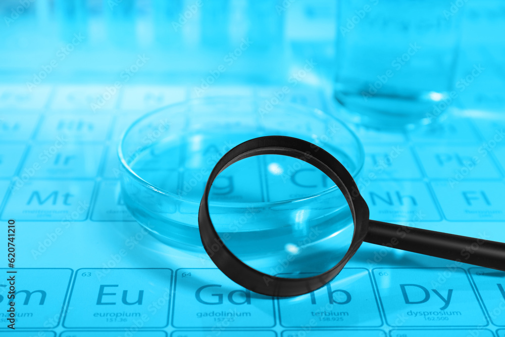 Petri dish, magnifying glass on periodic table of elements, closeup ...