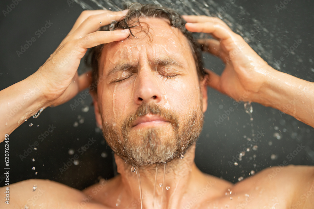 Millennial man washing hair in bath. Guy bathing shower head in bathtub ...