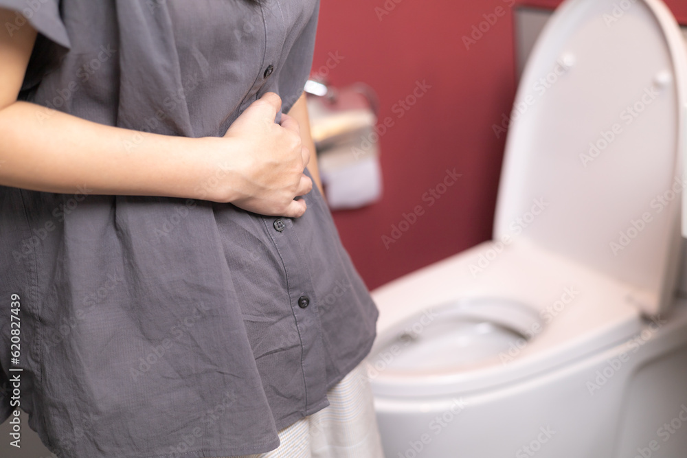 Young woman standing in the bathroom and putting her hand on her ...