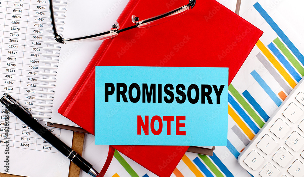 PROMISSORY NOTE text on a sticky on red notebook on chart background ...