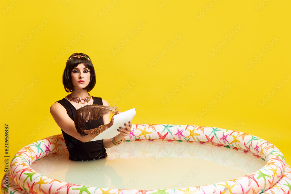 Serious young woman in image of Cleopatra sitting in swimming pool and ...