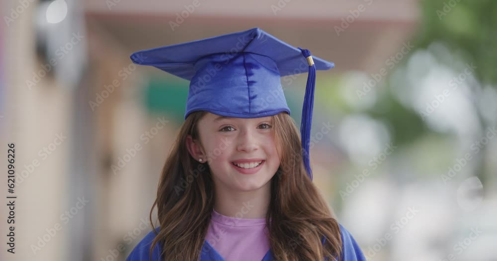 Girl in a blue graduation cap and gown shrugs and smiles at the camera ...