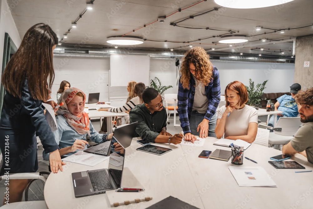 Long curly haired male employee helping his colleagues with financial ...