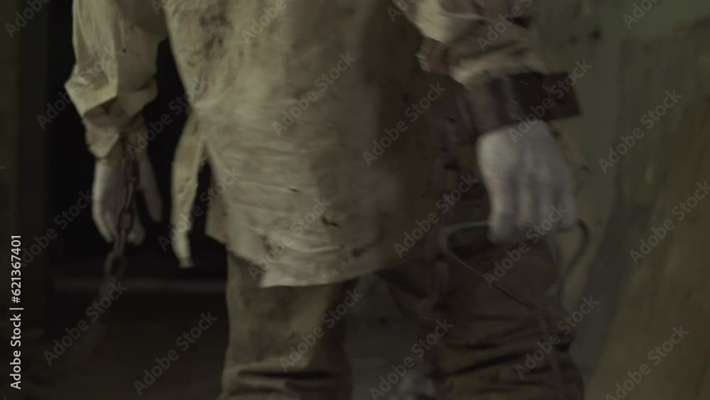 Ghost of maniac with cage on his head dragging dead body down corridor ...