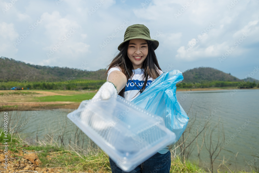Foto de Female volunteers showing plastic box garbage, conducting ...