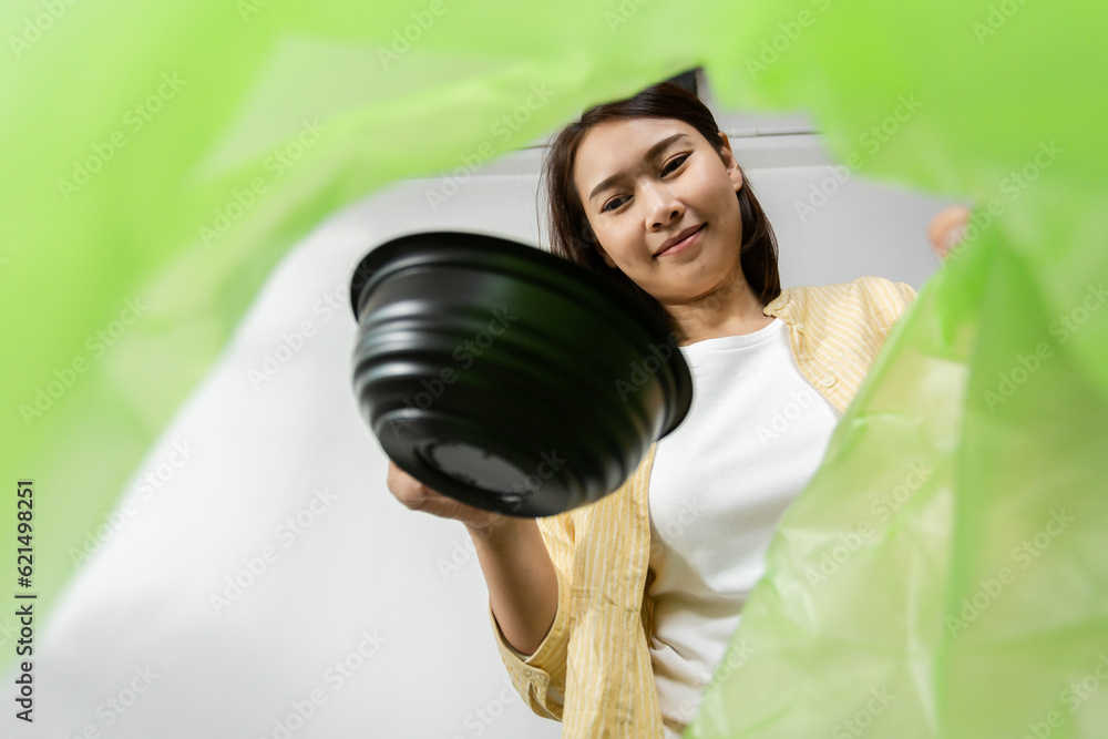Asian female holding black plastic cup waste into bags for recycling ...