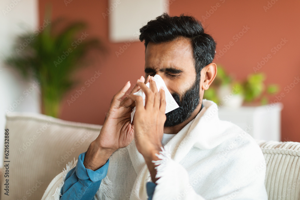 Arabic guy sneezing blowing runny nose in tissue at home Stock-Foto ...