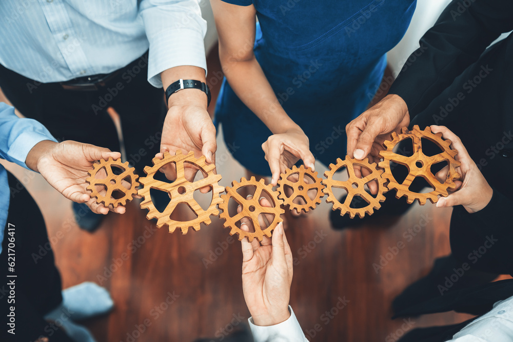 Office worker holding cog wheel as unity and teamwork in corporate ...