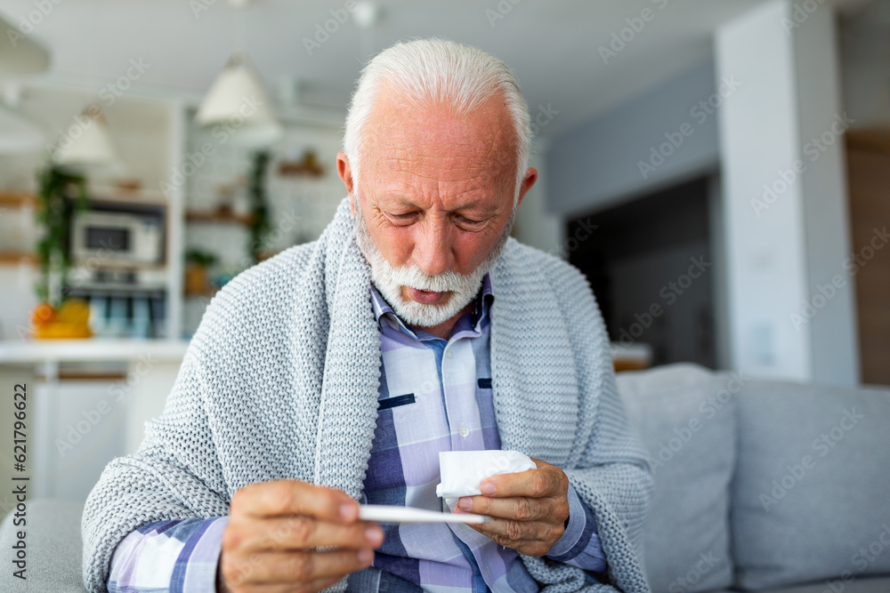 Elderly man checks temperature, battling the effects of seasonal flu or ...