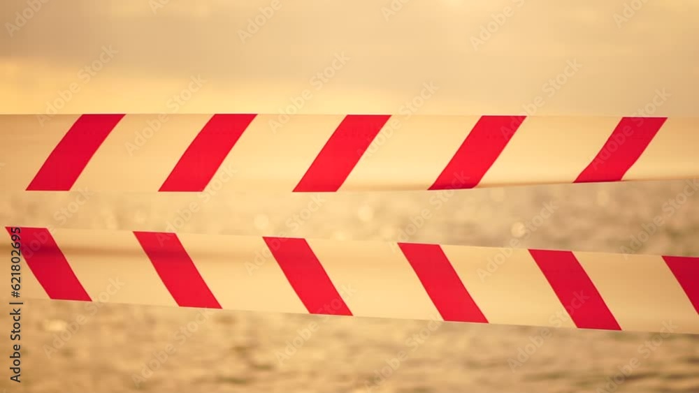 Red white warning tape barrier ribbon swinging in the wind across ...