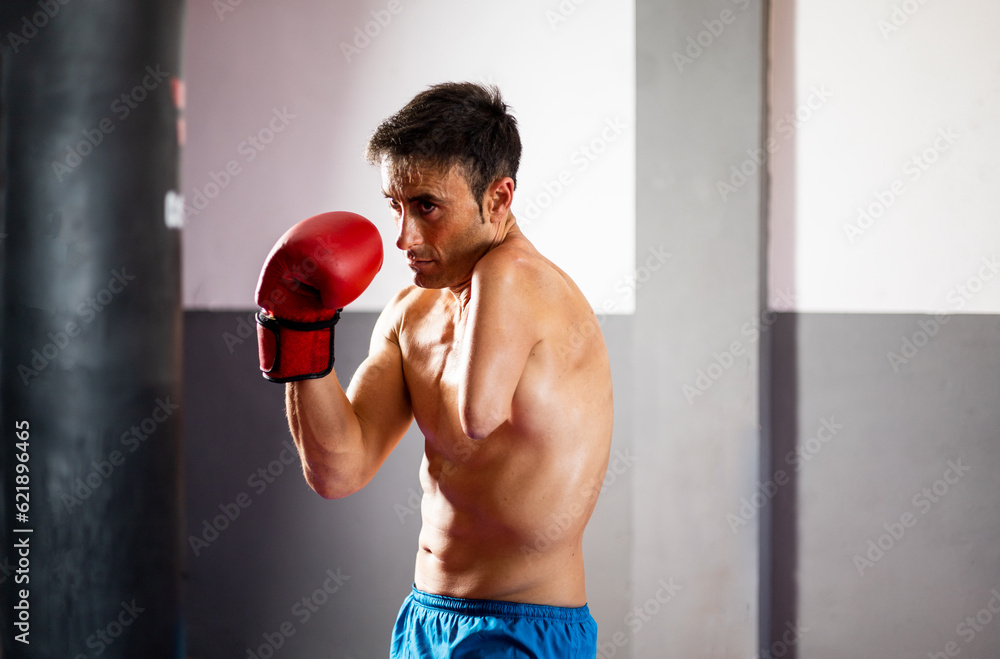 A shirtless boxer with an amputated arm is posing in front of a ...
