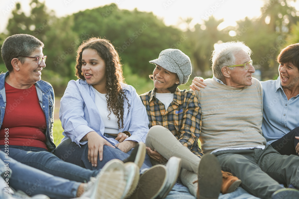 Multi generational people hugging each other while sitting at park ...