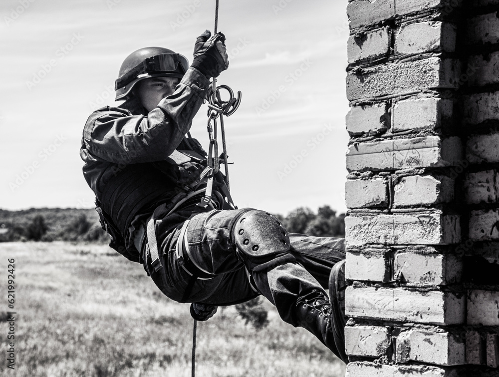 Silhouette of police officer in tactical gear descending from a height ...