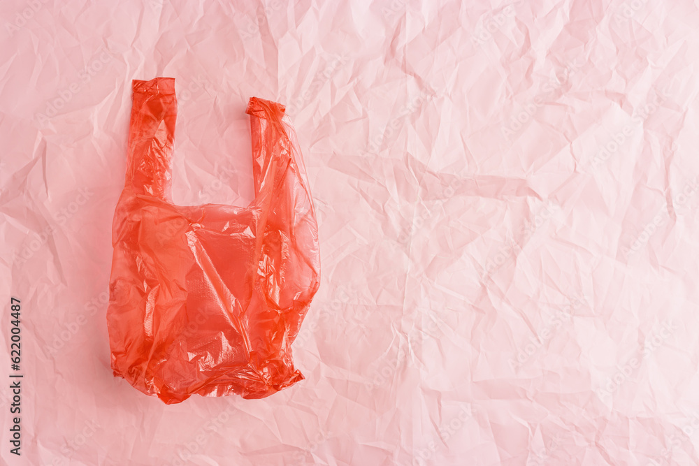 Red plastic bag on pink crumpled paper background, empty space ...