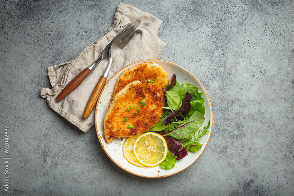 Crispy panko breaded fried chicken fillet with green salad and lemon on ...