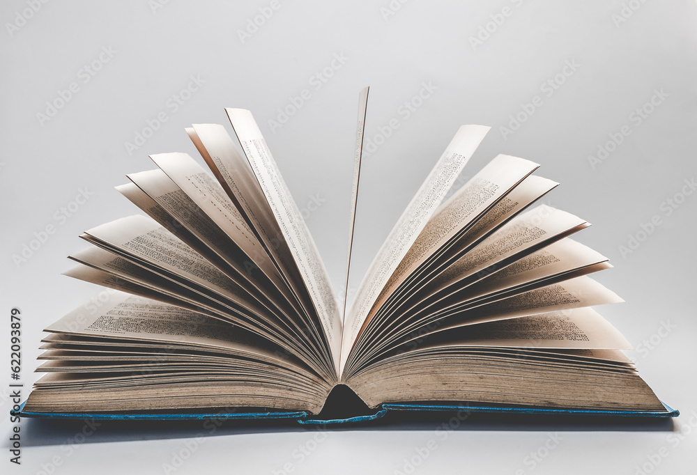 An old open story book on a white background with the pages fanning out ...