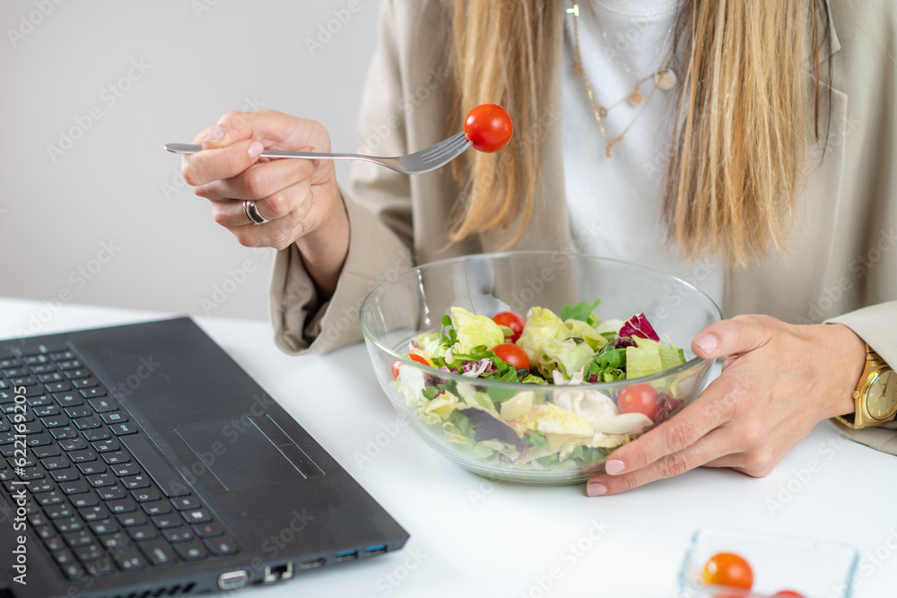 Foto de Healthy eating at work. Woman indulges in a delightful fresh ...