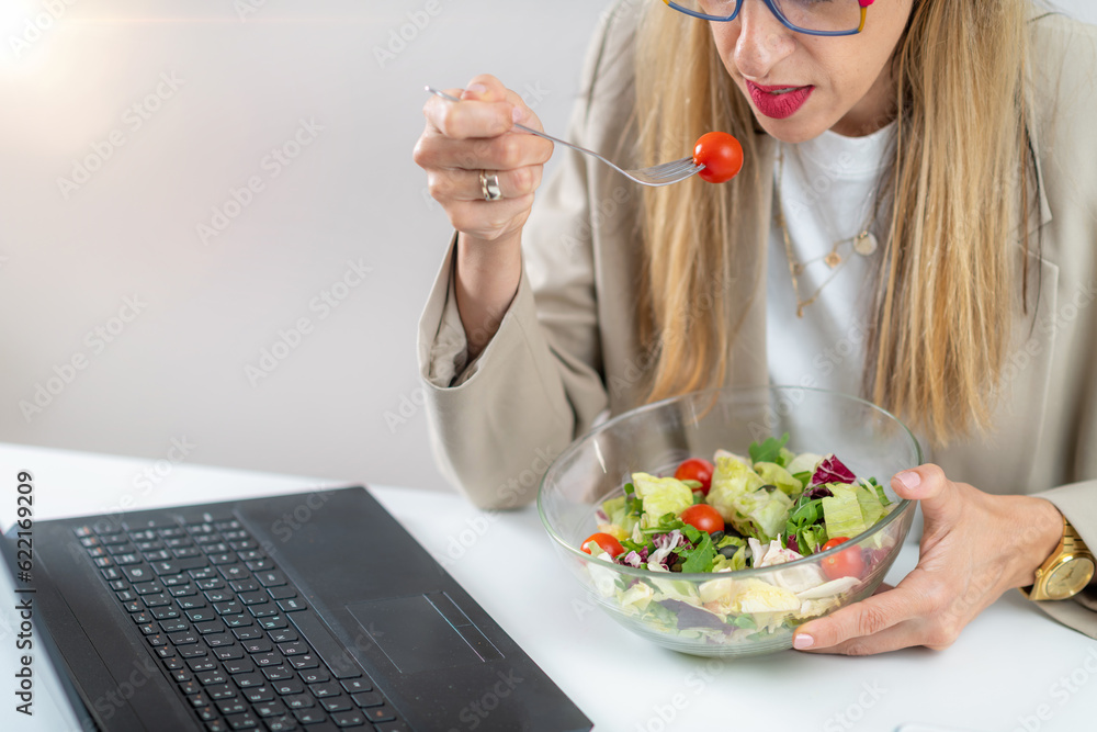 Foto de Healthy eating at work. Woman indulges in a delightful fresh ...