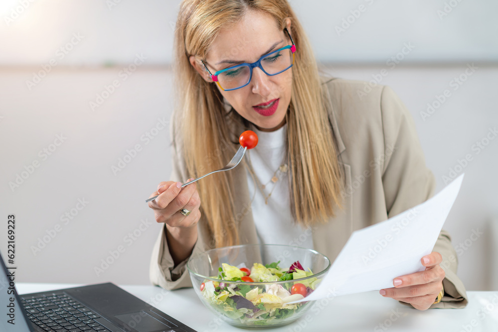 Foto de Healthy eating at work. Woman indulges in a delightful fresh ...