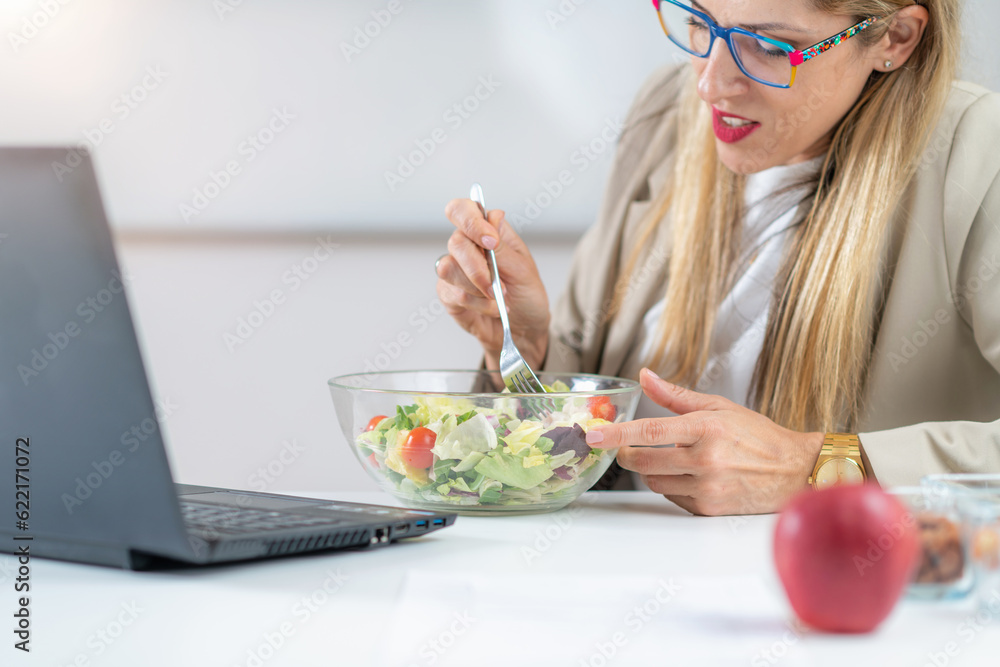 Foto de Healthy eating at work. Woman indulges in a delightful fresh ...