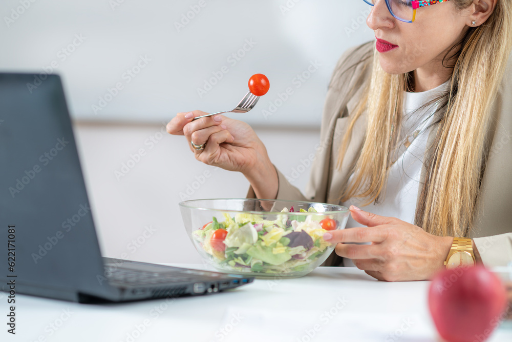 Foto de Healthy eating at work. Woman indulges in a delightful fresh ...