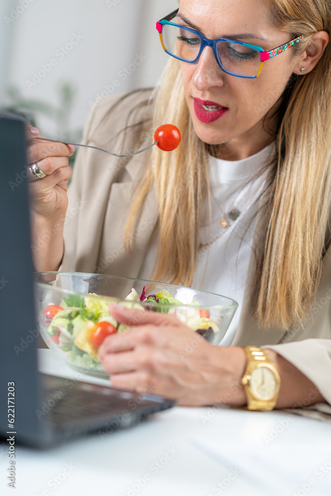 Foto de Healthy eating at work. Woman indulges in a delightful fresh ...