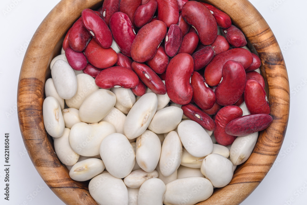 Surowa fasola czerwona i biała ułożone w drewnianej miseczce na białym ...