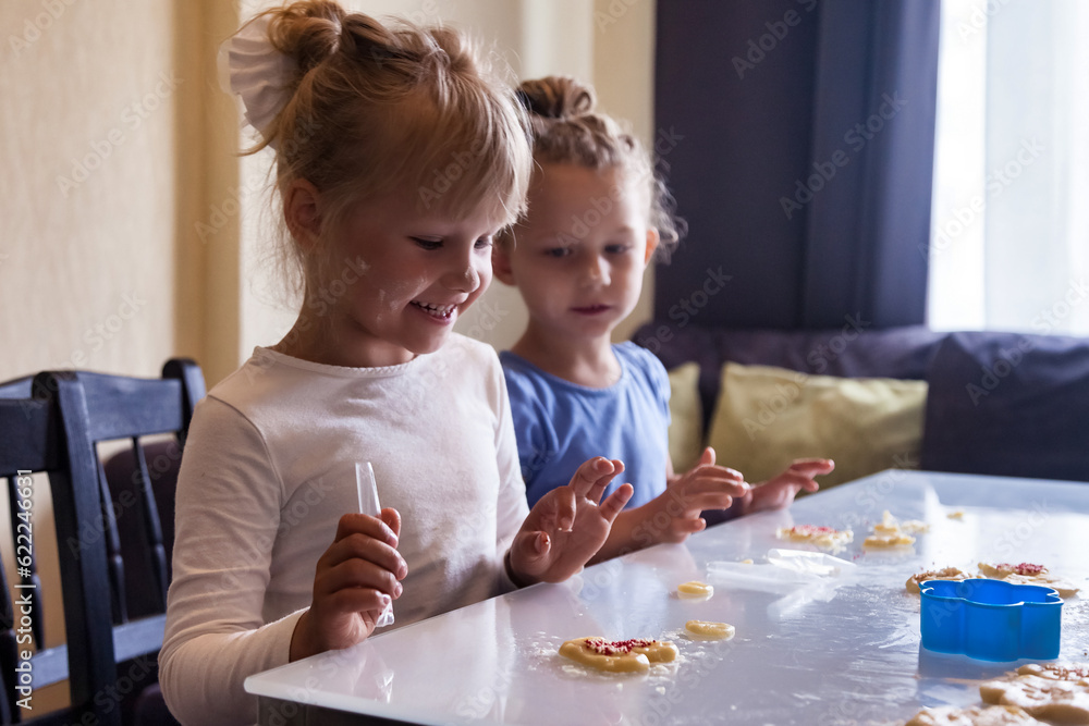 Two little girls kids cooking cookies from dough and flour in kitchen ...