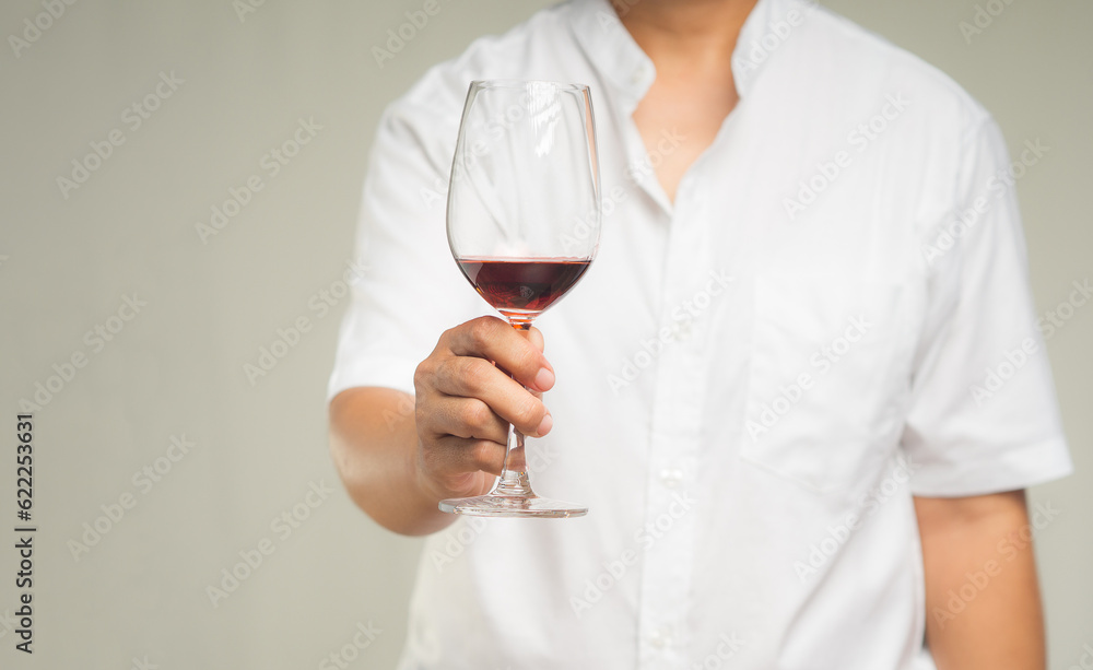Close-up of hand holding a glass of red wine while standing on a gray ...