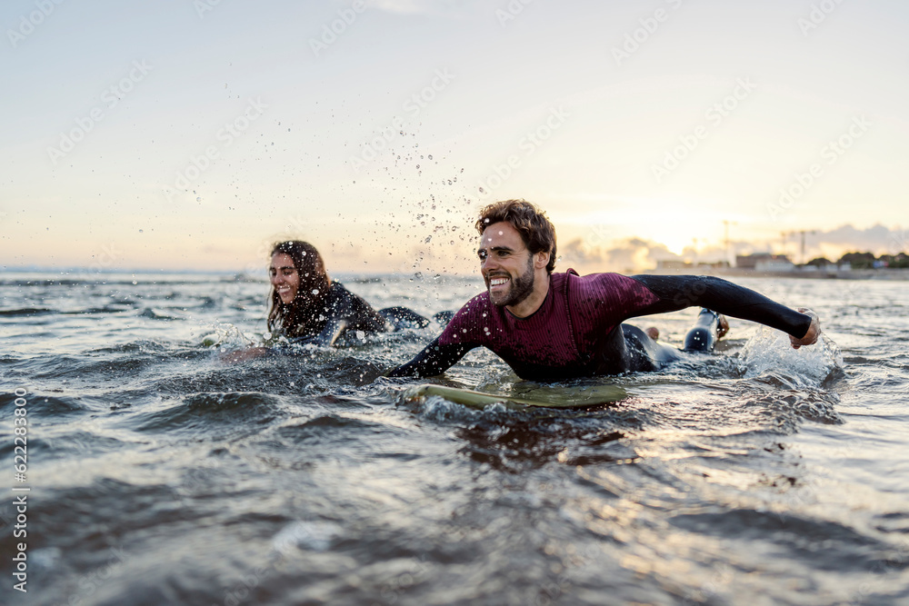 Surfers swimming towards waves in the ocean. Stock Photo | Adobe Stock