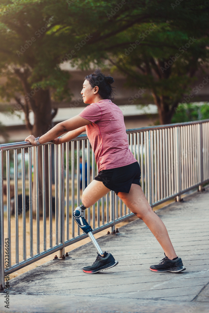 Athlete with prosthetic leg doing warm up exercise on park. Woman ...