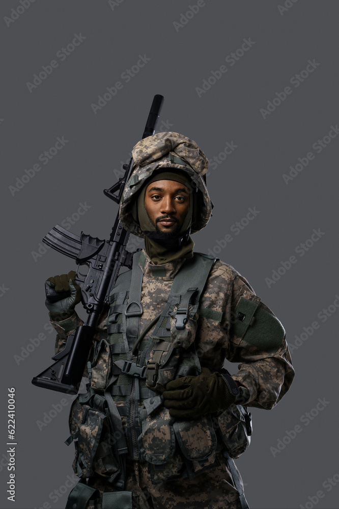 Confident soldier in NATO uniform and helmet poses with his rifle on a ...